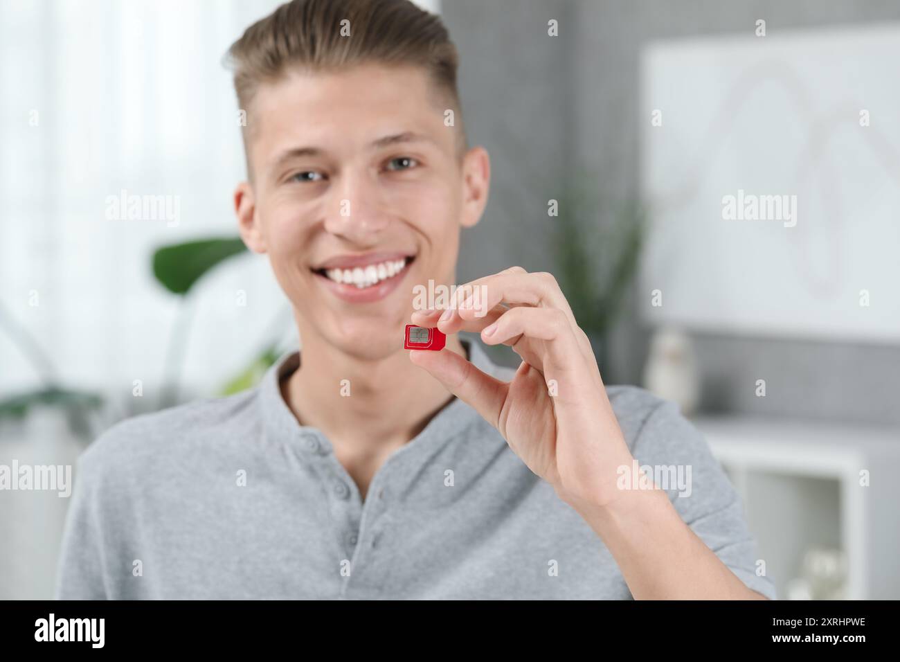 Happy man with SIM card at home Stock Photo - Alamy