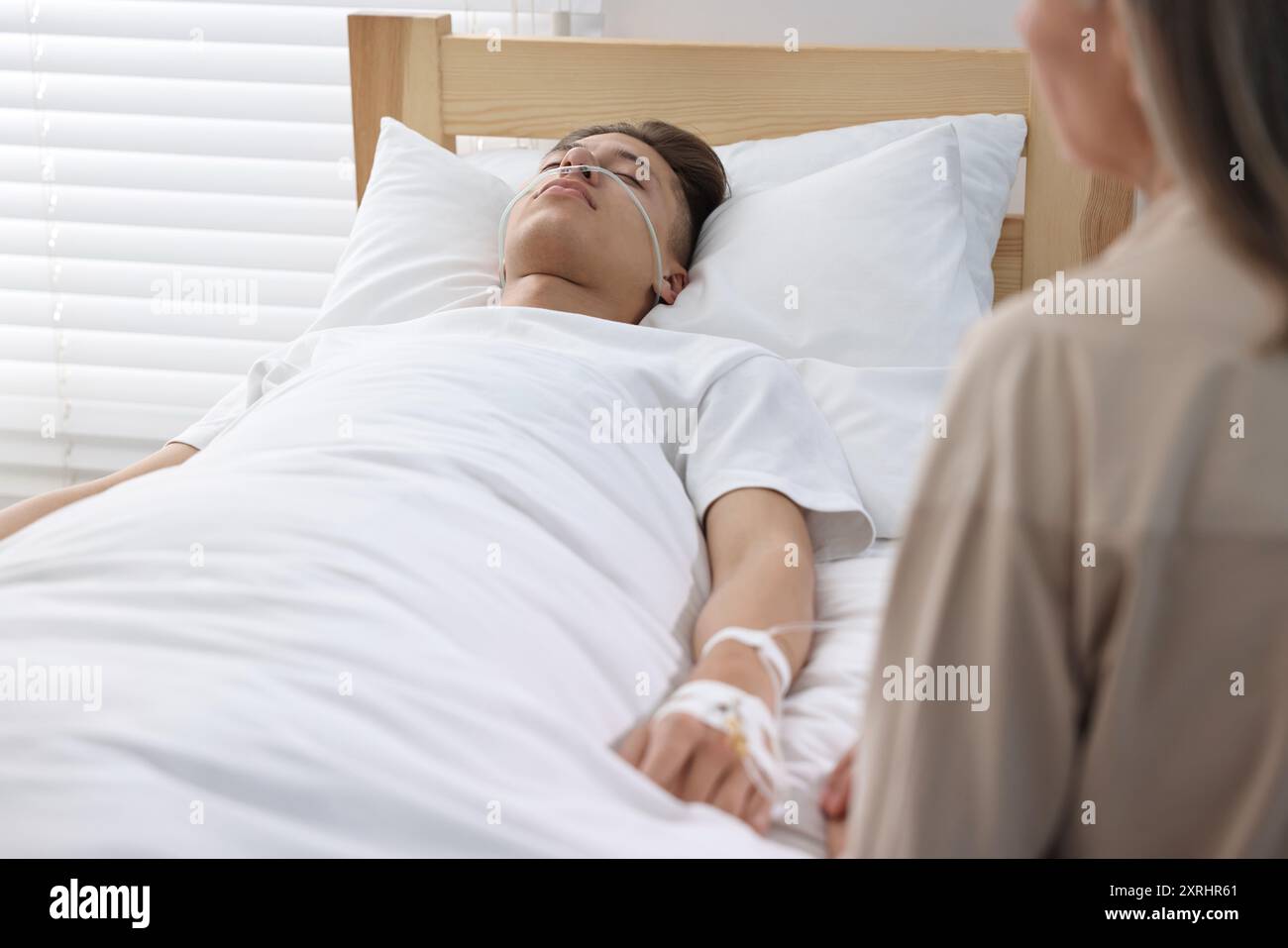 Coma patient. Sad mature woman near her unconscious son in hospital ...
