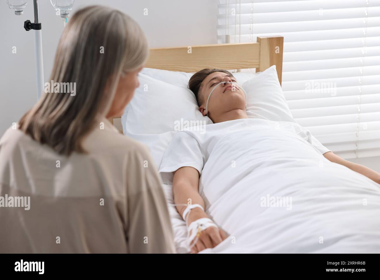 Coma patient. Sad mature woman near her unconscious son in hospital ...