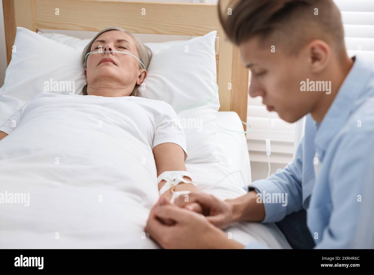 Coma patient. Sad young man near his unconscious mother in hospital Stock Photo - Alamy