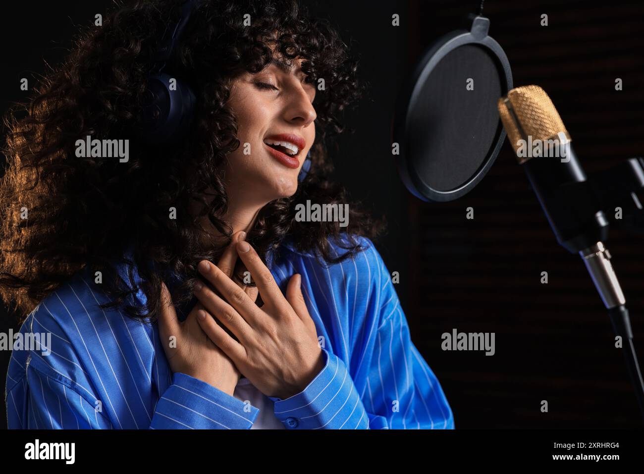 Vocalist with headphones singing into microphone in professional record ...