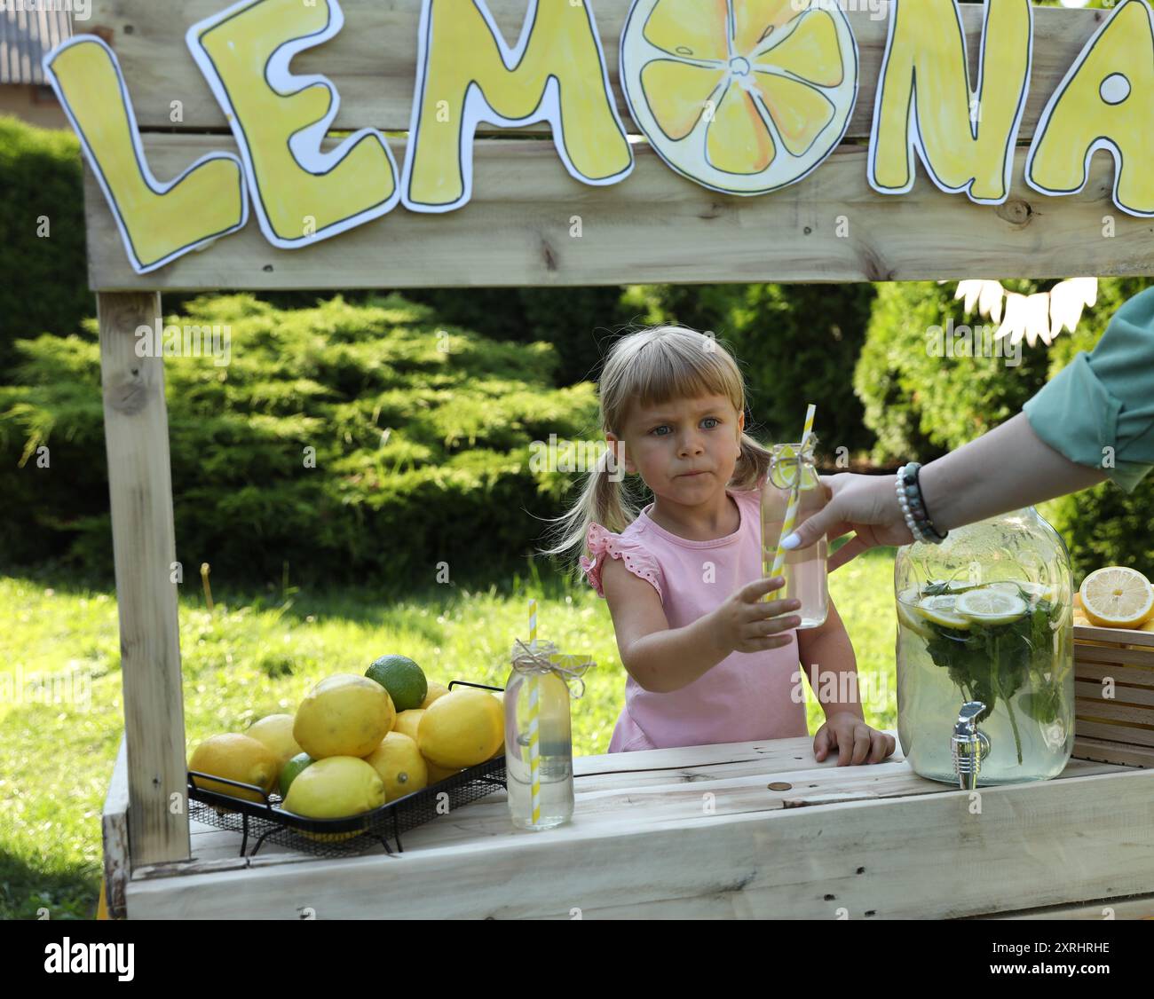 Cute little girl selling natural lemonade to woman in park Stock Photo ...