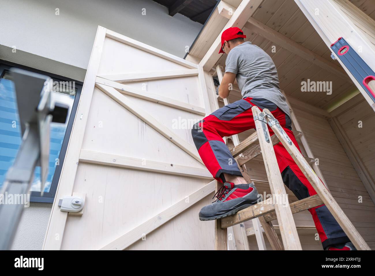 A person is fixing a wooden door while using a ladder, showcasing a ...