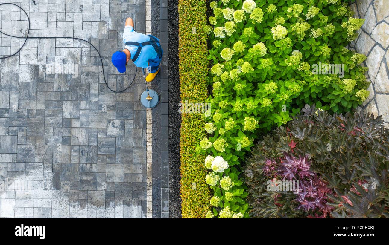 A worker carefully tends to the greenery and floral arrangements in a ...