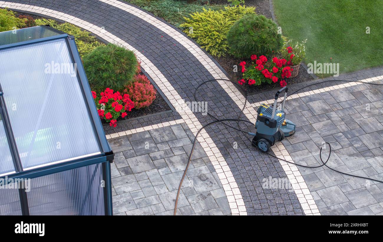 A pressure washer rests on a stone patio, surrounded by colorful ...