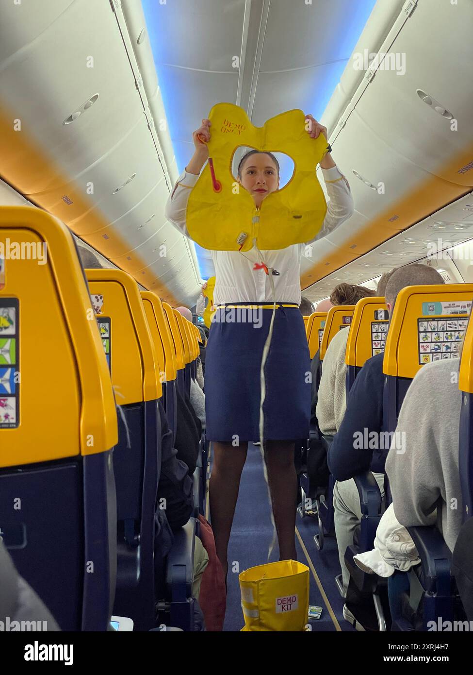 A flight attendant demonstrates the use of an inflatable flotation ...
