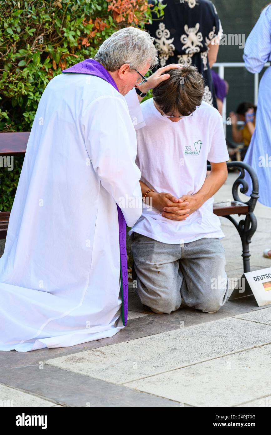 A Catholic priest blessing and giving absolution to a penitent after ...