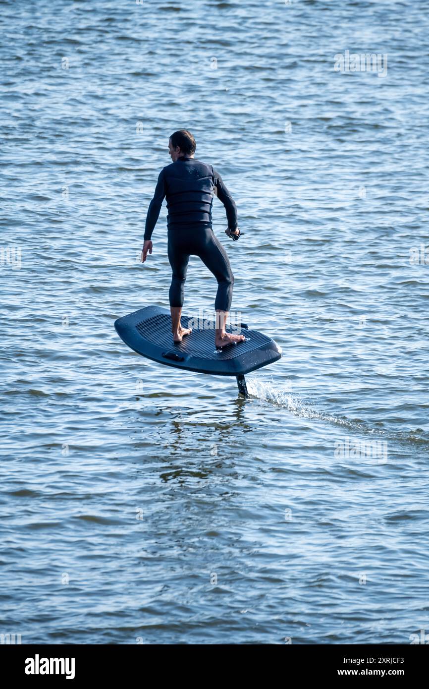 Surfer rides electric hydrofoil board above choppy water, showcasing ...