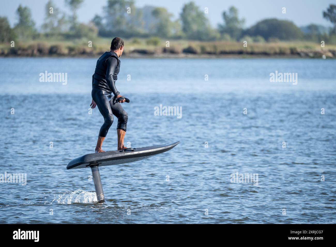 A man glides effortlessly on an electric hydrofoil surfboard ...