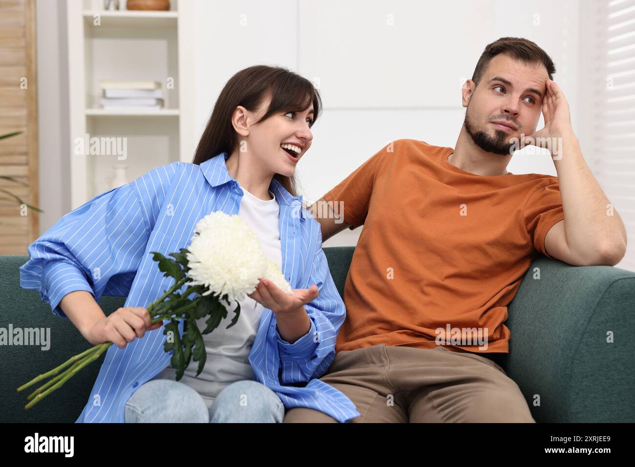 Obsessive woman with flowers flirting with embarrassed man at home ...