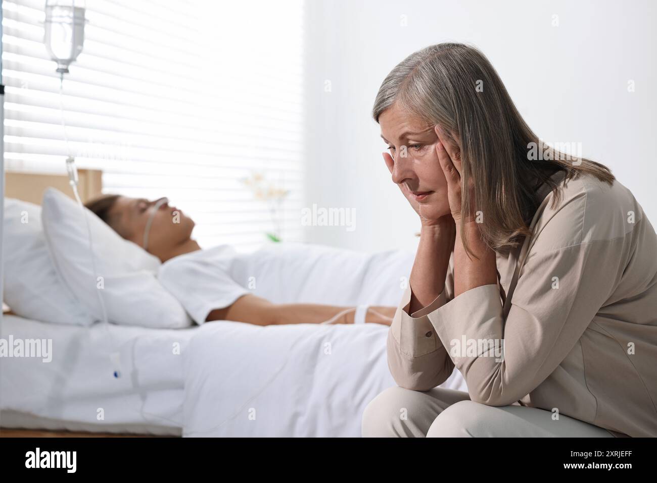 Coma patient. Sad mature woman near her unconscious son in hospital ...