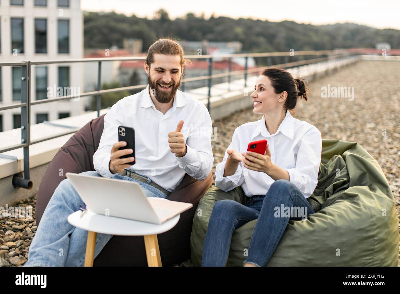 Young professionals working on rooftop with mobile devices Stock Photo ...