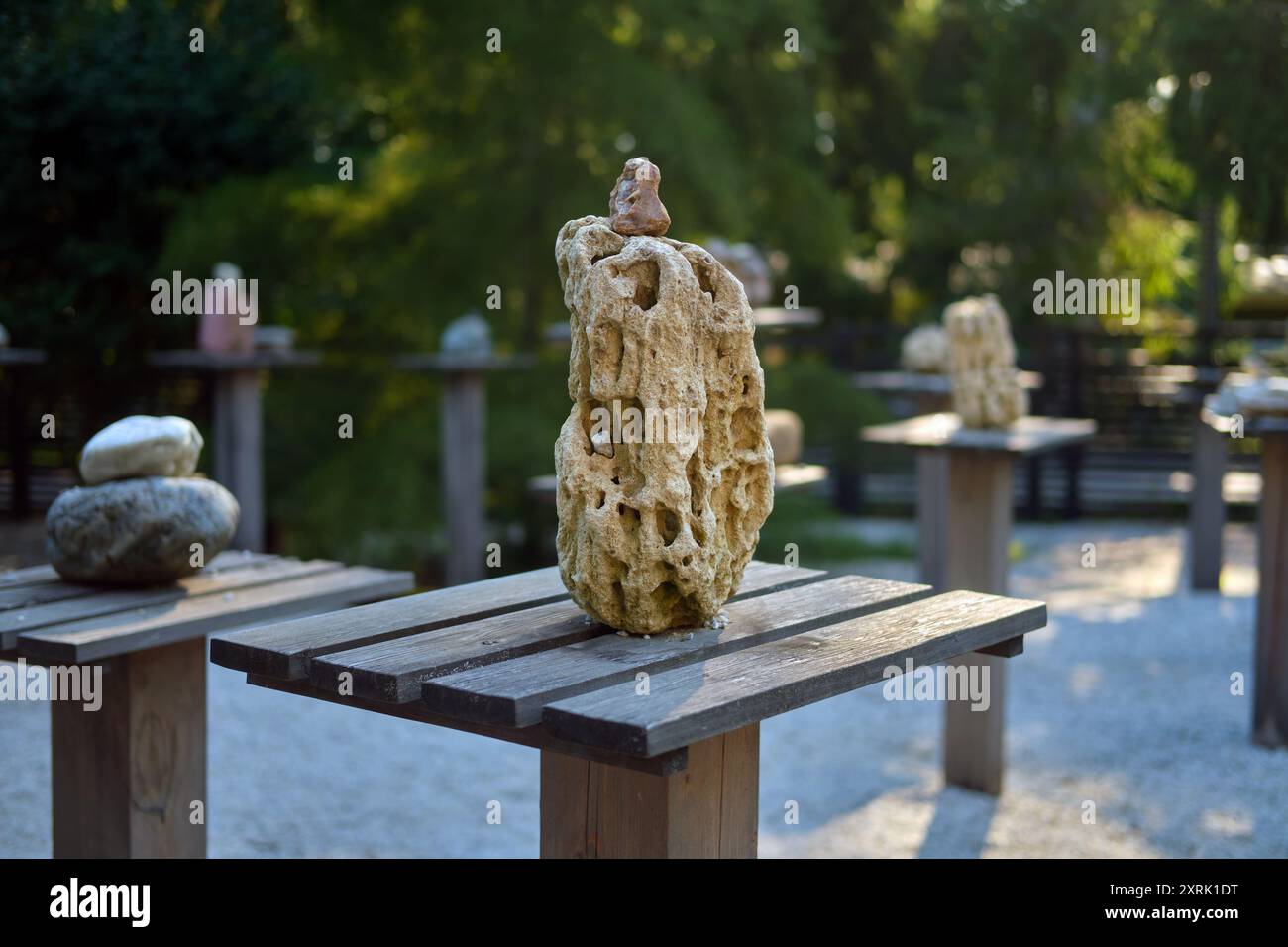 Porous stone sculpture displayed on a wooden pedestal in an outdoor ...