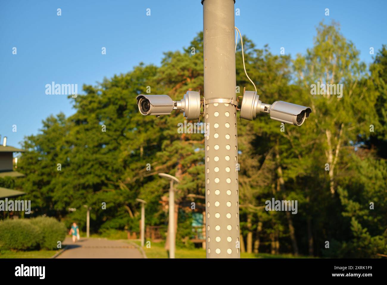 Two security cameras mounted on a metal pole in an outdoor park ...