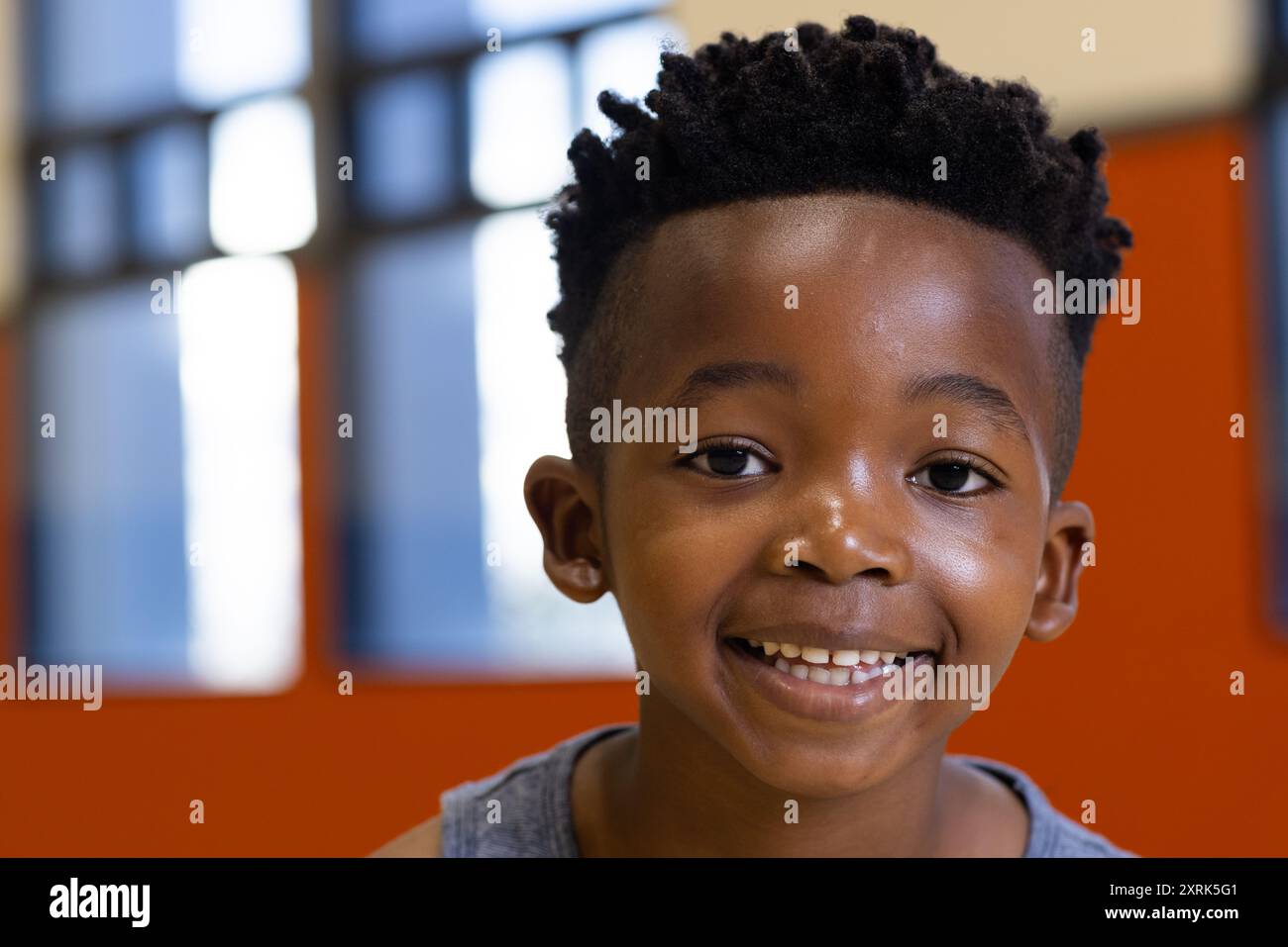 Smiling boy in school classroom, looking at camera with joy and ...