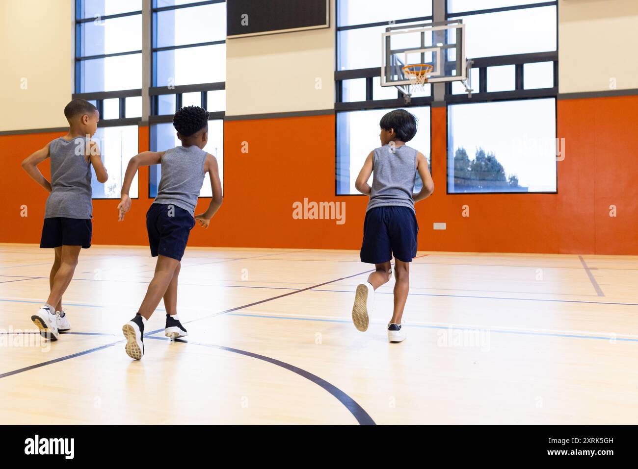 Running in gym, three boys exercising during school physical education ...