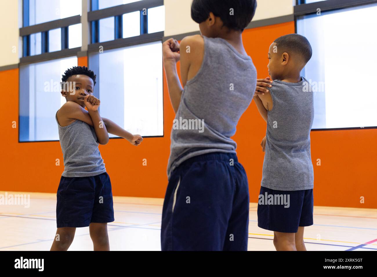 In school gym, boys stretching arms during physical education class ...