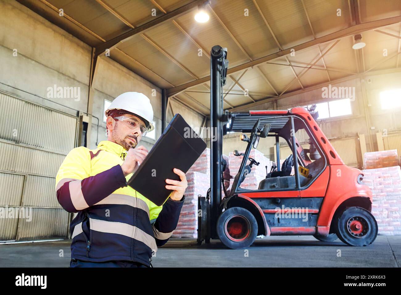 Warehouse Worker Checking Inventory Beside Forklift Stock Photo - Alamy