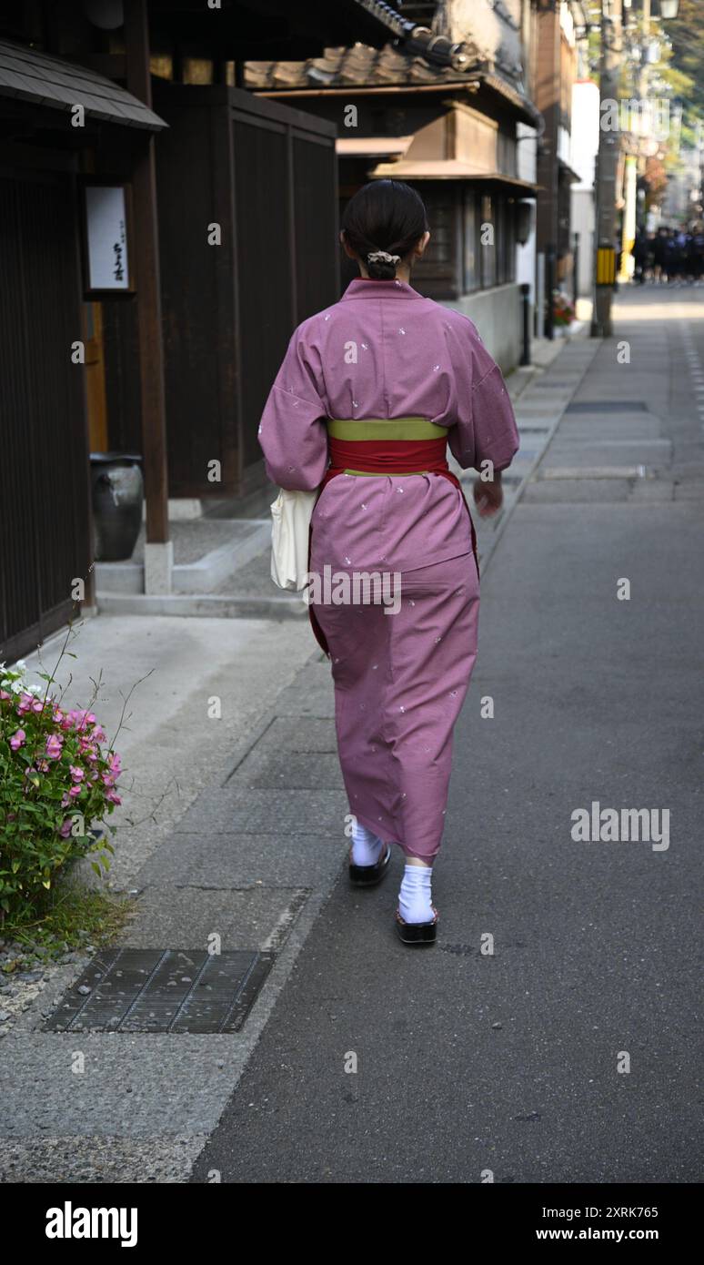 Young Japanese girl wearing the traditional yukata walking on the streets of the Edo period ...