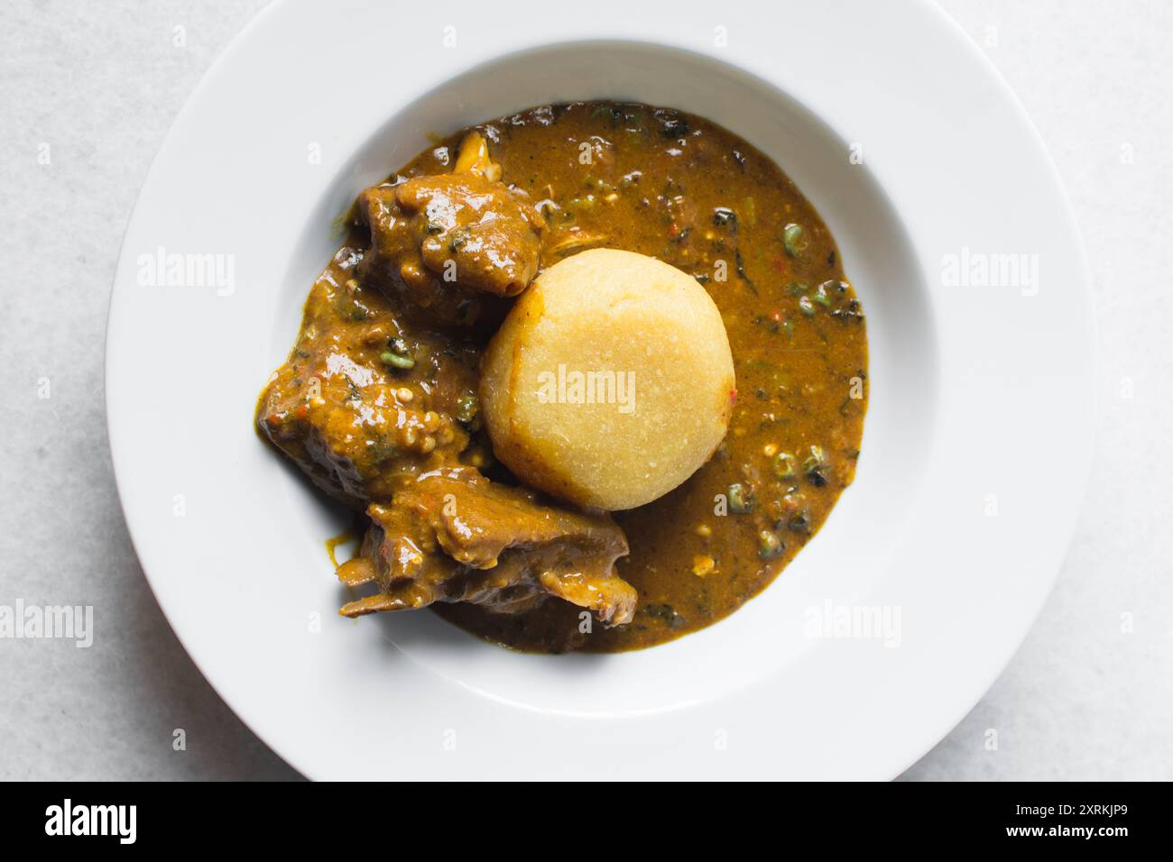 Overhead view of nigerian ogbono soup and eba on a white plate, top ...