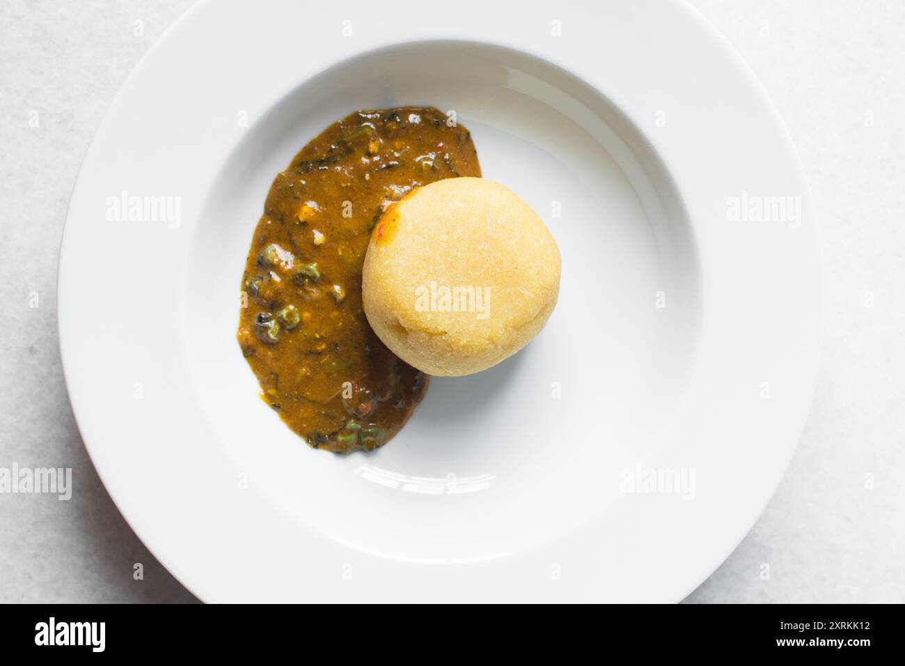 Overhead view of nigerian ogbono soup and eba on a white plate, top ...