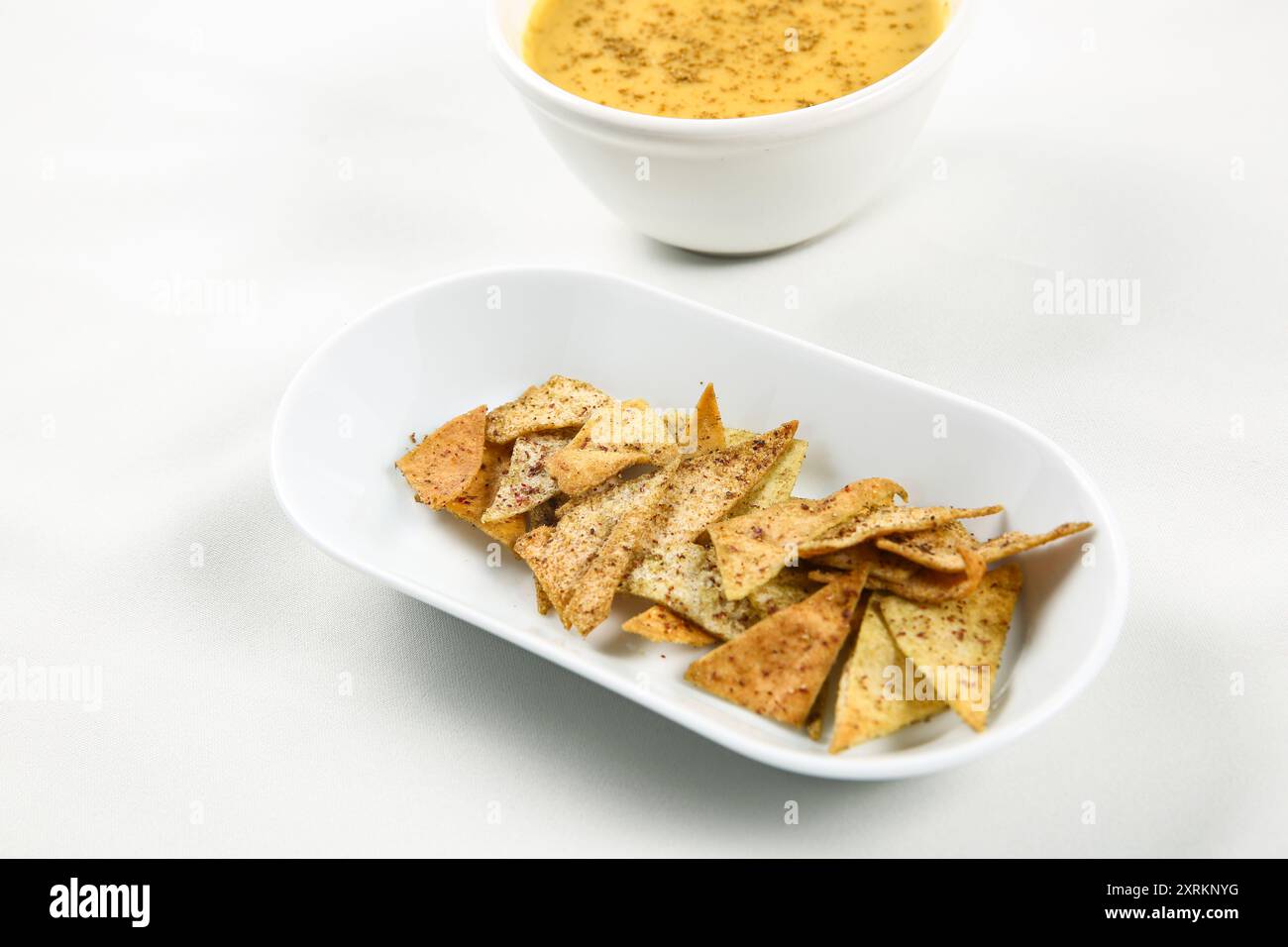 Top view of homemade spicy pita chips with dip. Chips and dip are in a ...