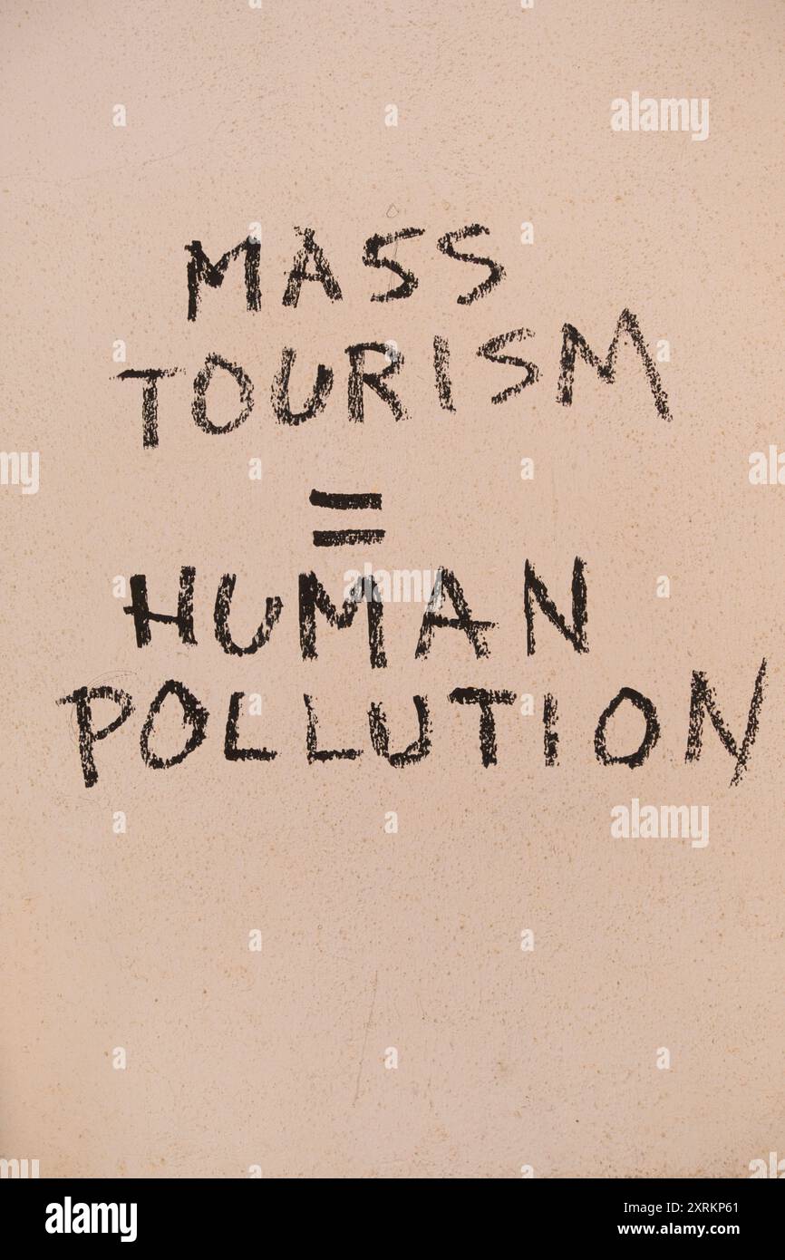 Mass tourism = human pollution graffiti on the wall of a building Stock ...
