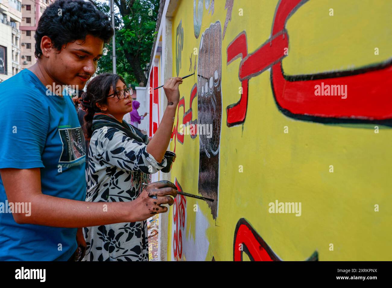 Students paint a new graffiti on a street wall in Dhaka, Bangladesh ...