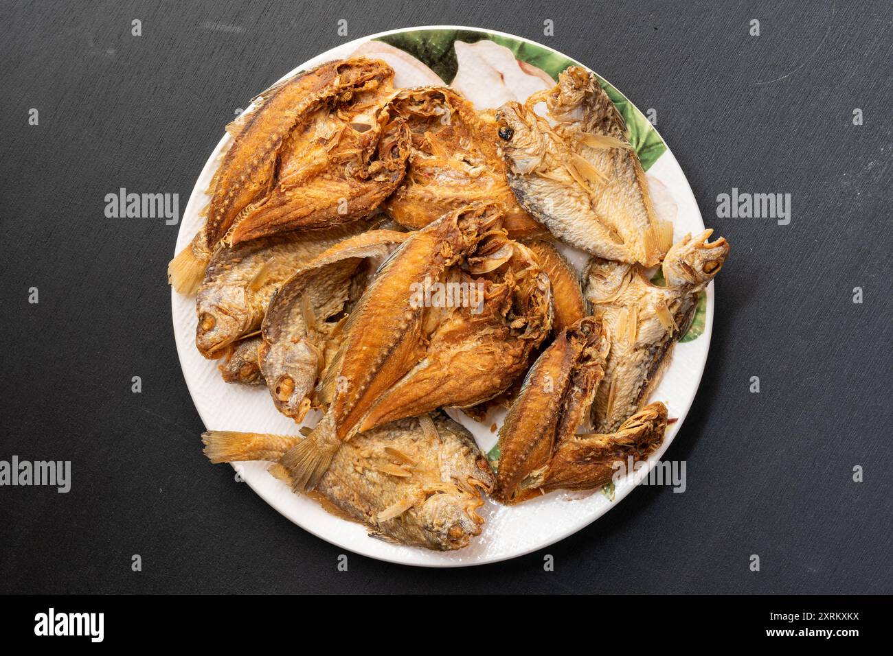 Ikan masin goreng or fried salted fish in white plate, isolated on ...