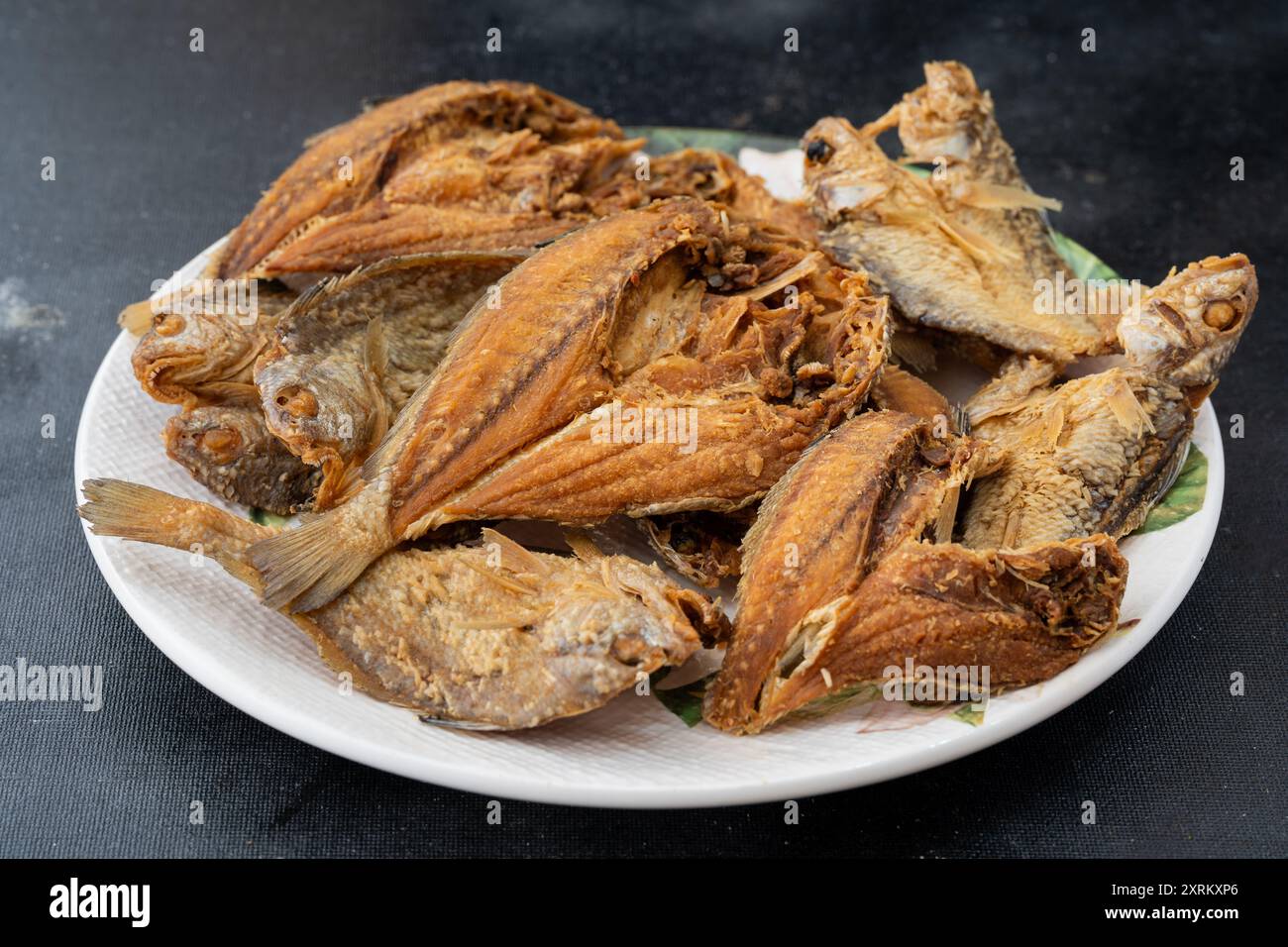 Ikan masin goreng or fried salted fish in white plate, isolated on ...