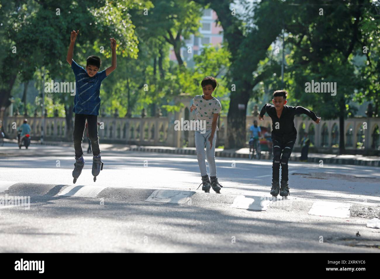 Three children are enjoying roller skating on the empty road during ...