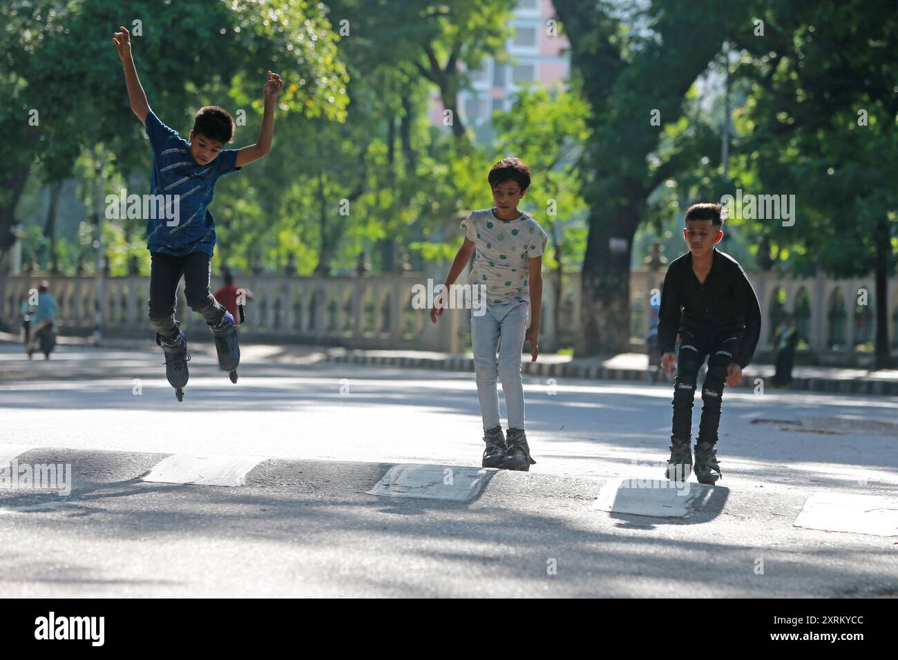 Three children are enjoying roller skating on the empty road during ...