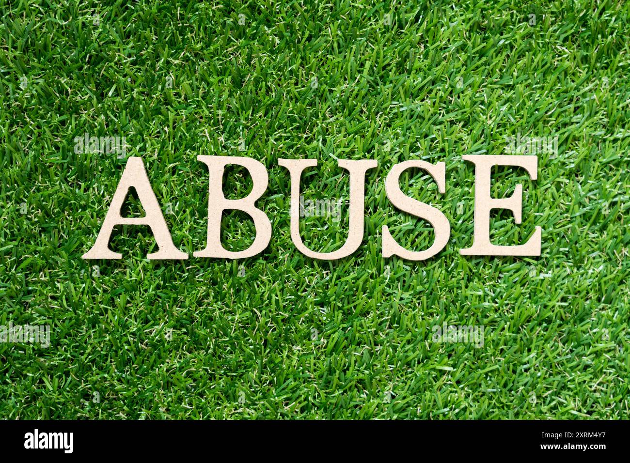 Wood alphabet letter in word abuse on artificial green grass background ...