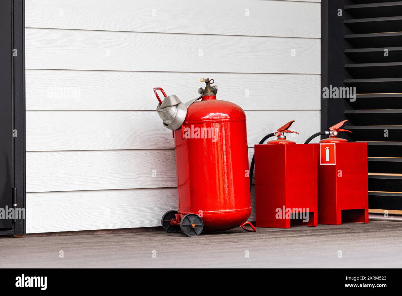 a red mobile fire extinguisher stands near the house Stock Photo - Alamy