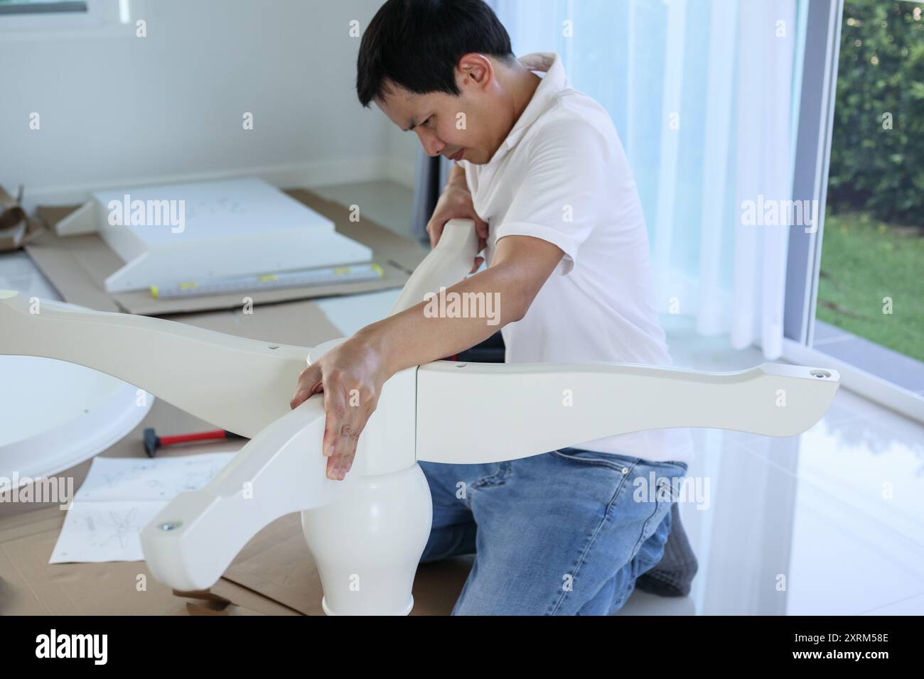 Asian man assembling white table furniture at home Stock Photo - Alamy