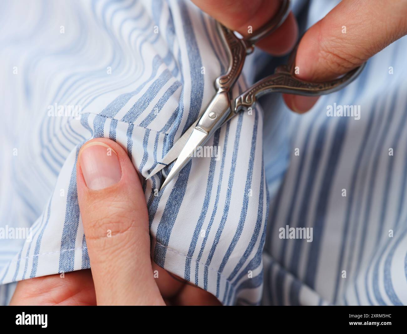 Woman hands with scissors cutting open the basting stitch on the dress ...