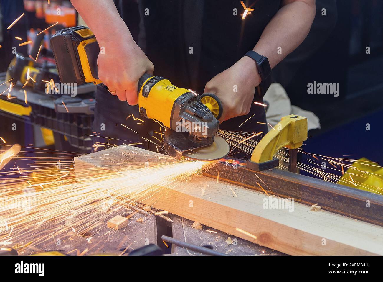 Craftsman using a grinder to cut metal in a workshop with sparks flying ...