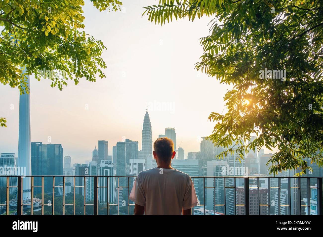 Rear view of man standing on the rooftop terrace of high rise building ...