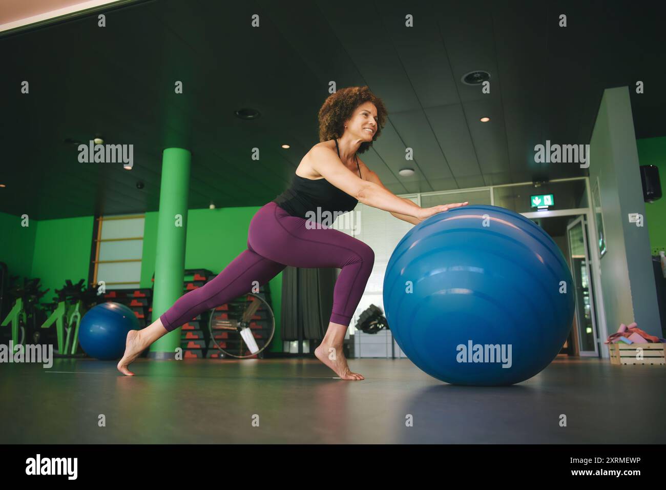 Portrait of mature 50 - 55 year old woman traing with fitness ball at ...