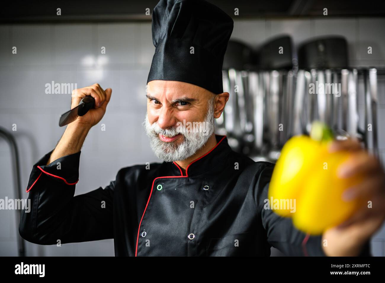 Chef in a busy kitchen playfully holds a yellow pepper, adding humor to ...