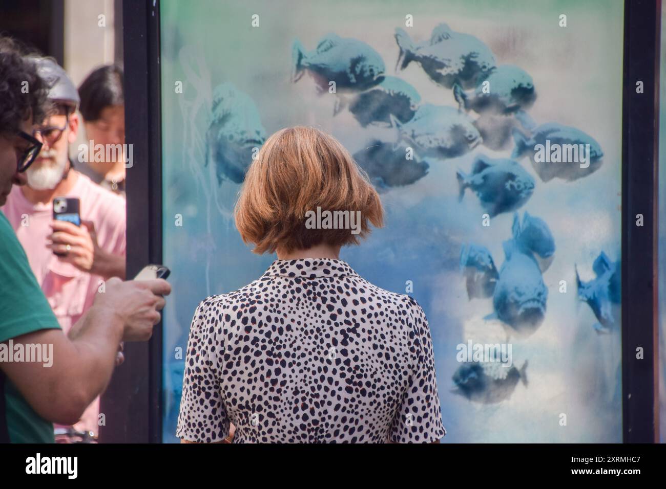 London, UK. 11th August 2024. A woman takes photos of the new Banksy ...