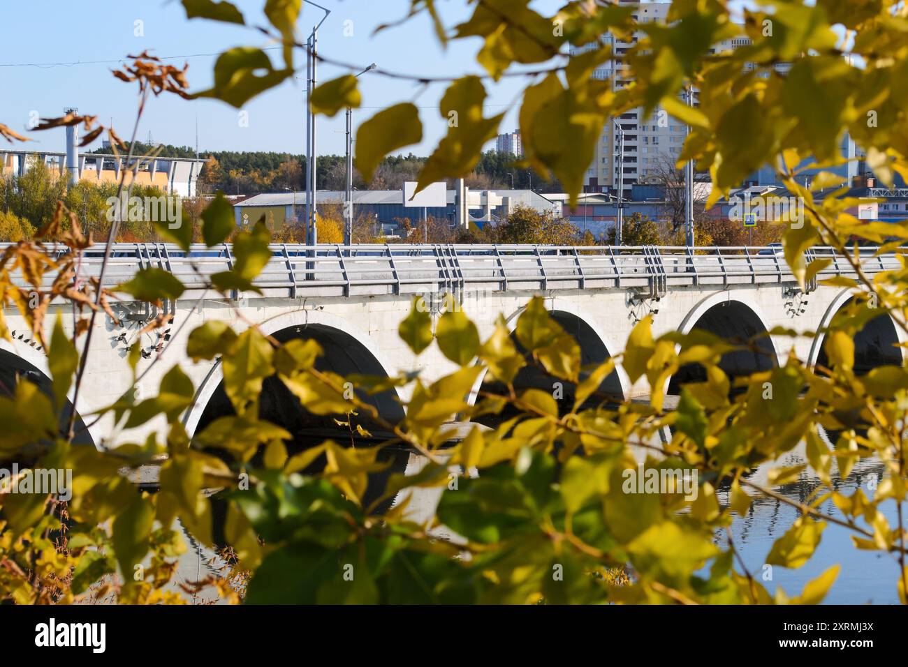 View through the autumn foliage on a modern arched bridge across the ...