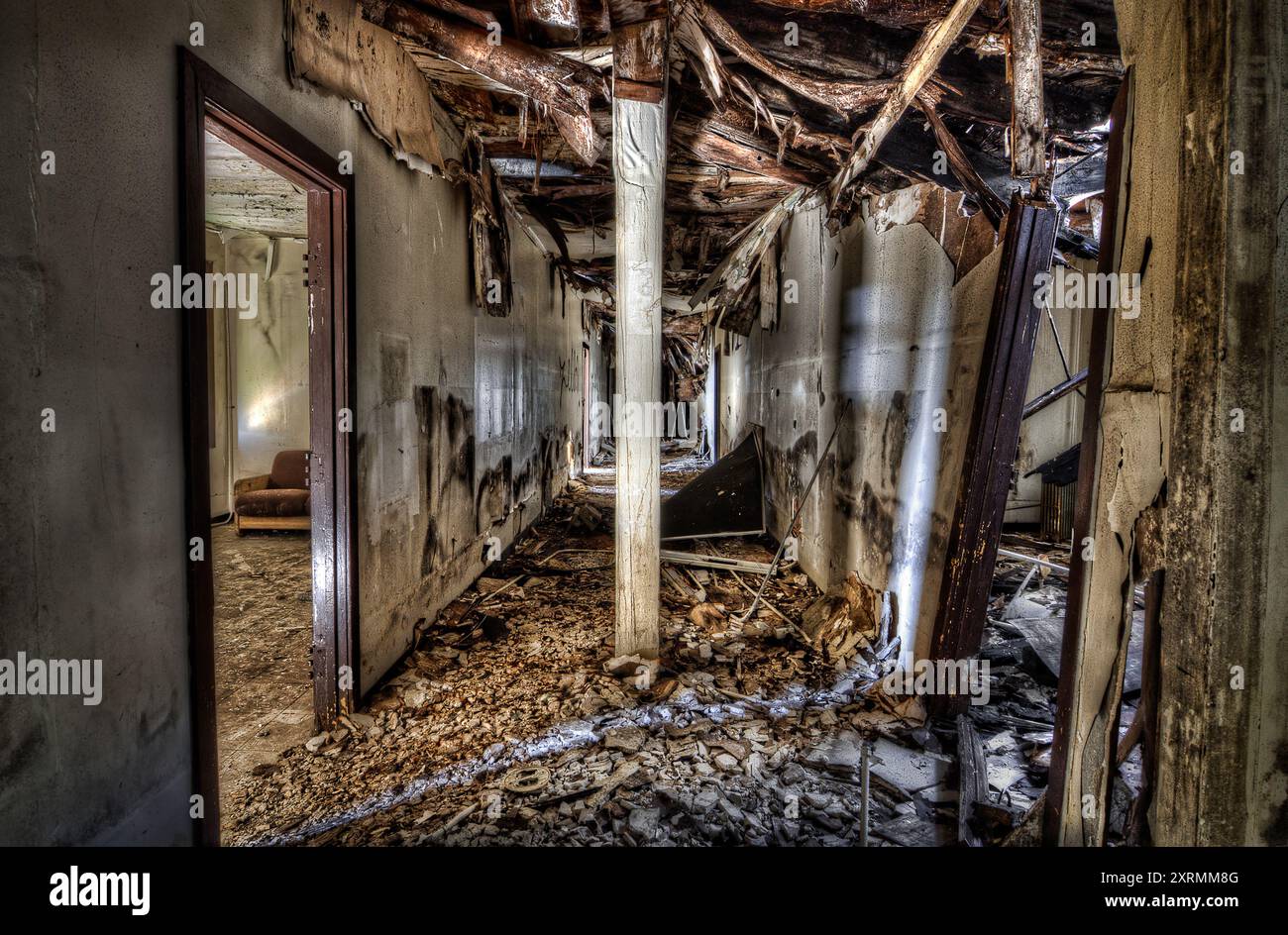 An old hallway with walls that are crumbling, broken doors and peeling ...