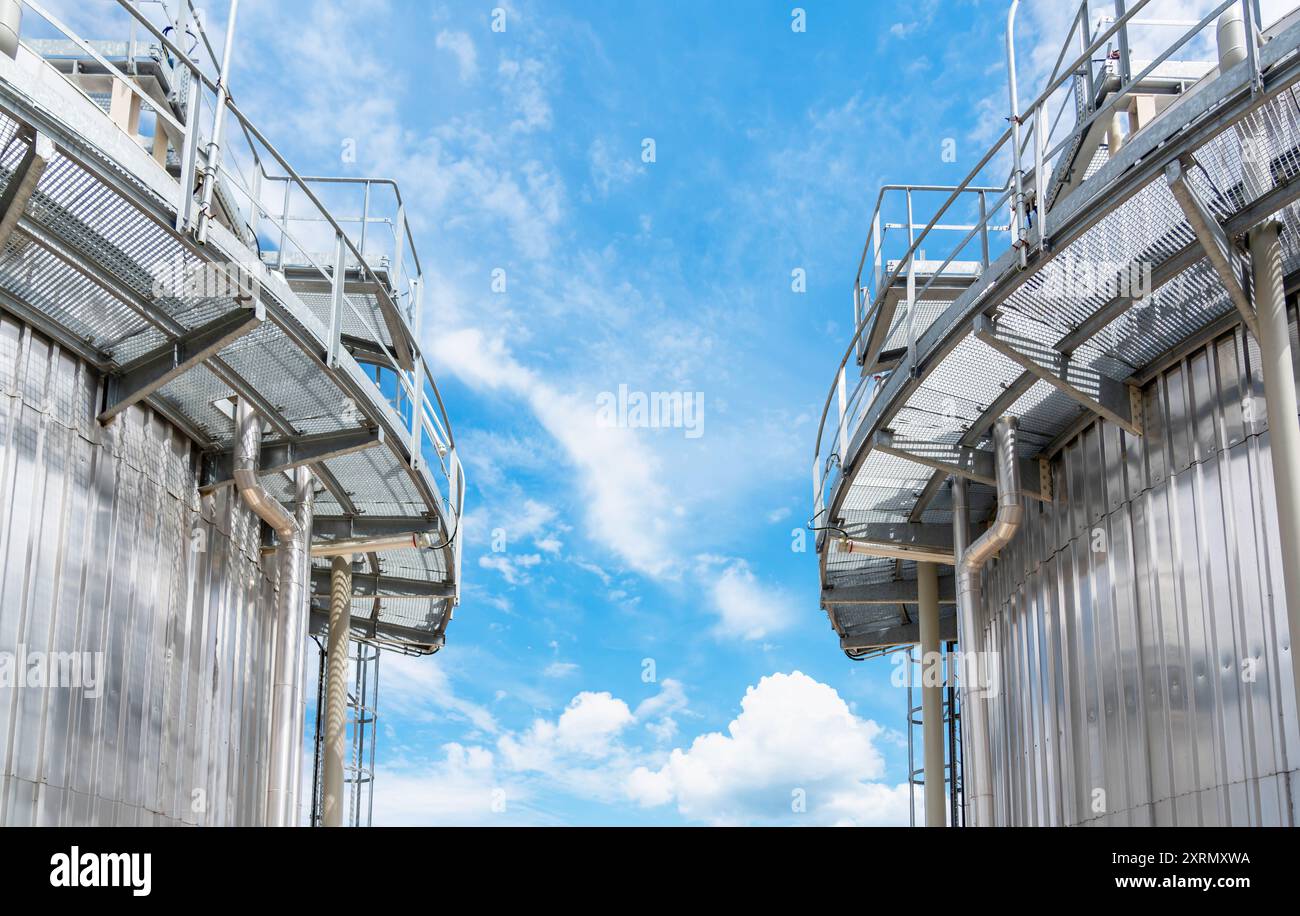 Two large metal tanks in a production facility surrounded by pipes ...