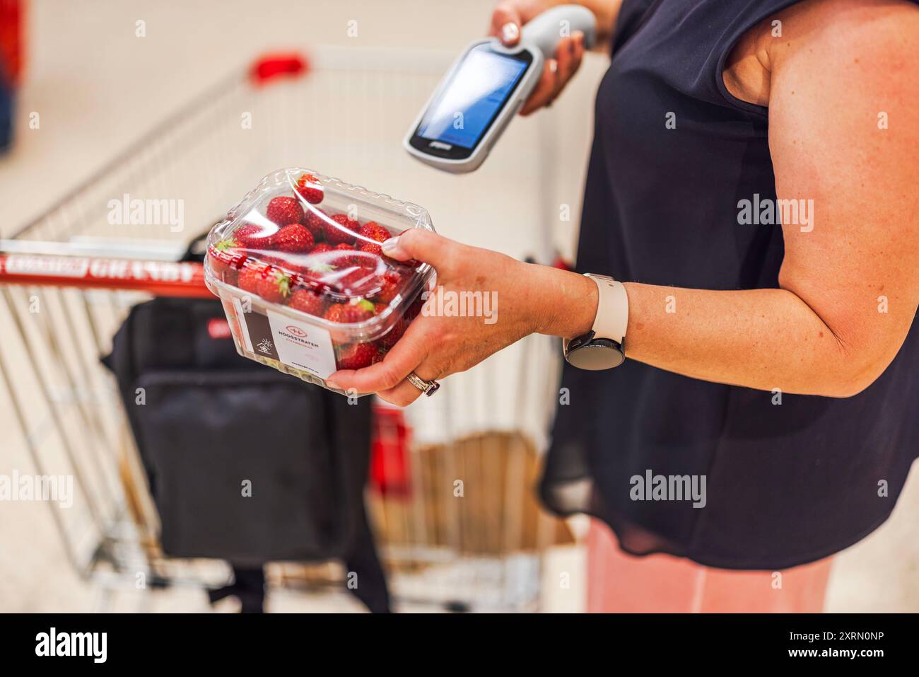 Woman scans a package of strawberries at a supermarket using a barcode ...