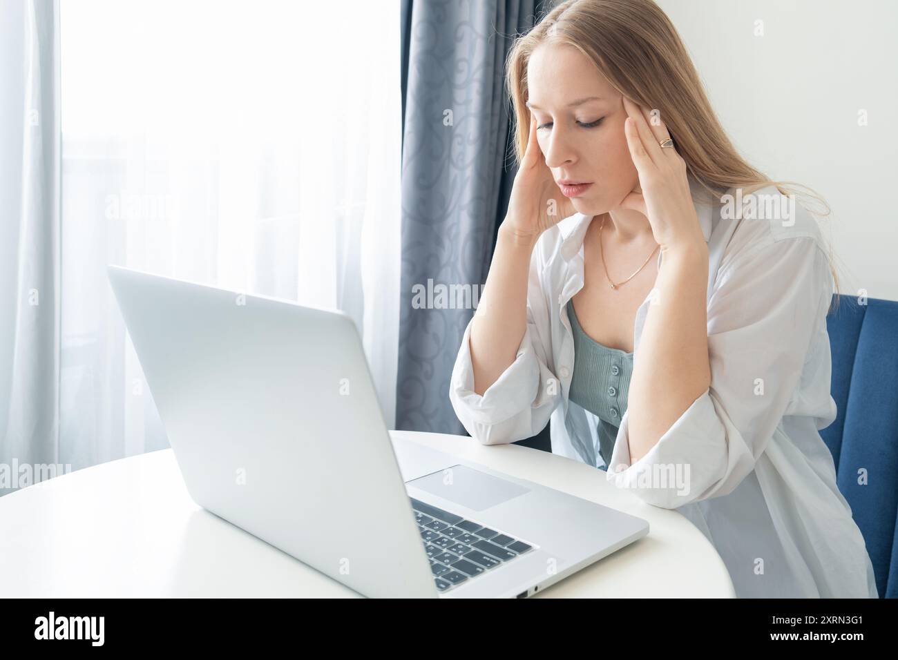 Stressed business woman working at home on laptop with headache feeling ...