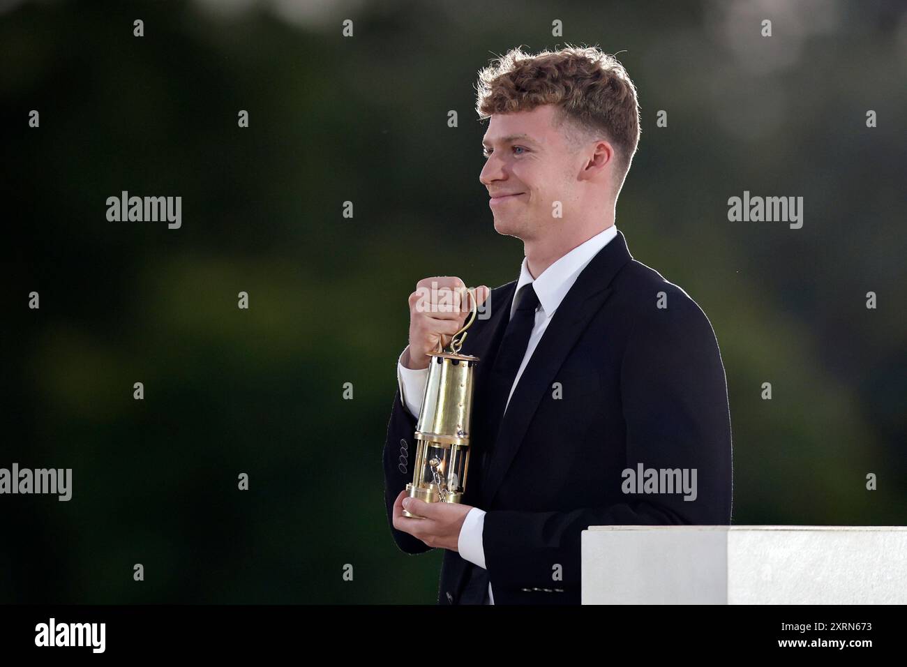 French swimmer Leon Marchand carries the Olympic flame at the Gardens ...