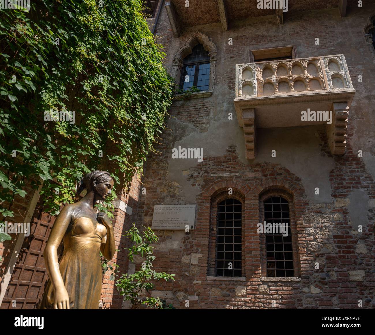 Verona, Italy - June 06, 2024: Bronze statue of Juliet and balcony by ...