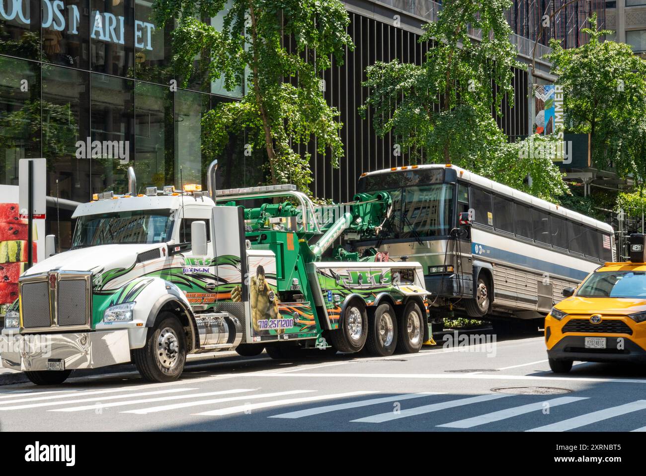 An inoperative bus is attached to a tow truck on Madison Avenue in NoMad Manhattan, New York ...