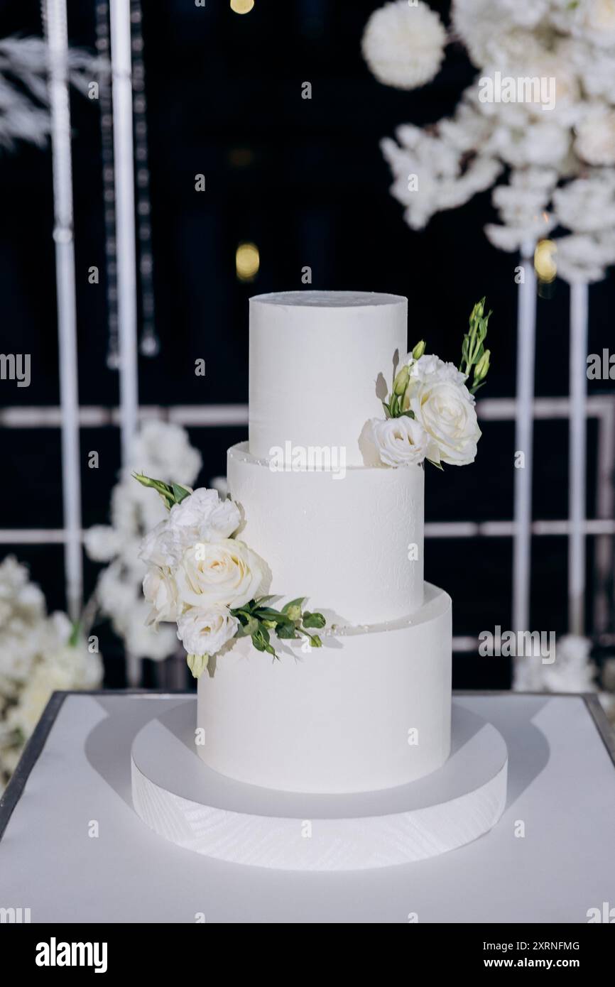 Wedding setup with three-tier white cake with floral accents. Wedding ...